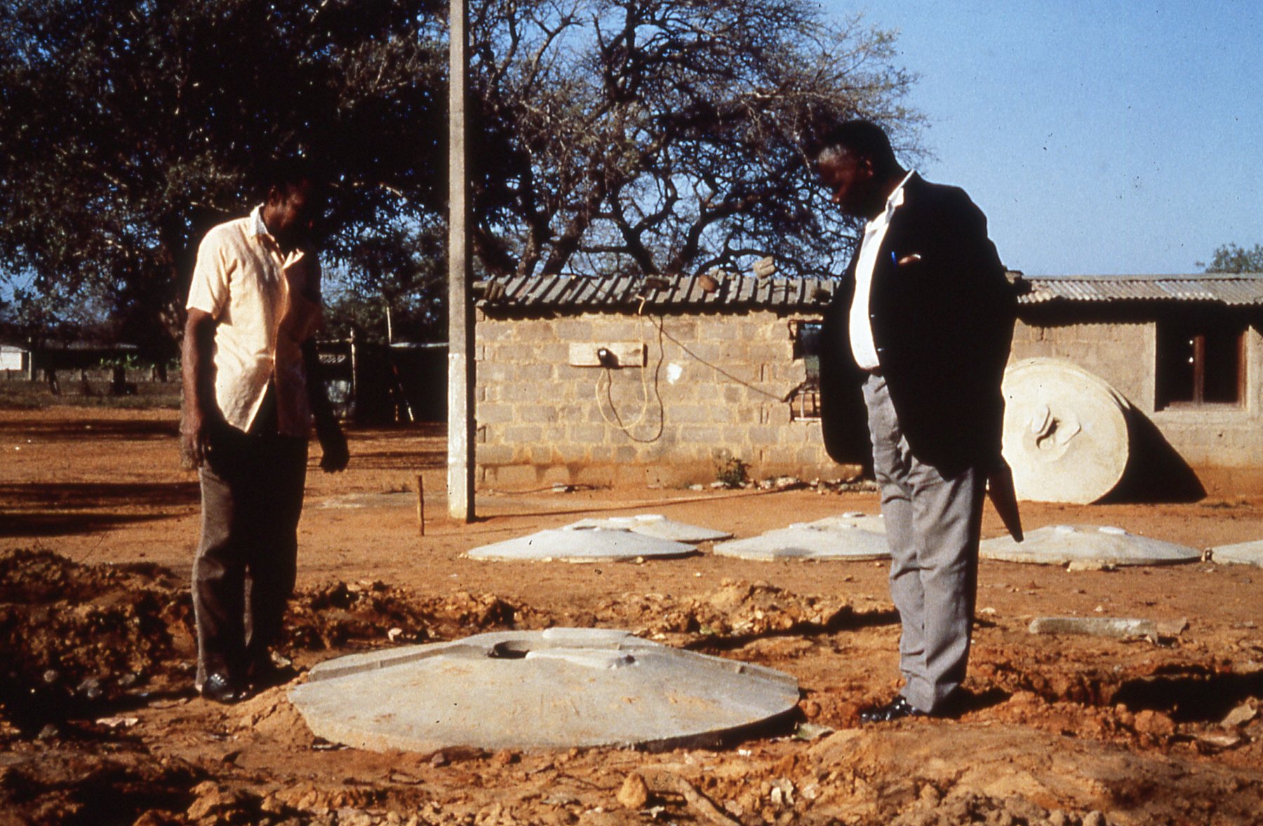 Men inspect new latrine cover | DW Digital Archive